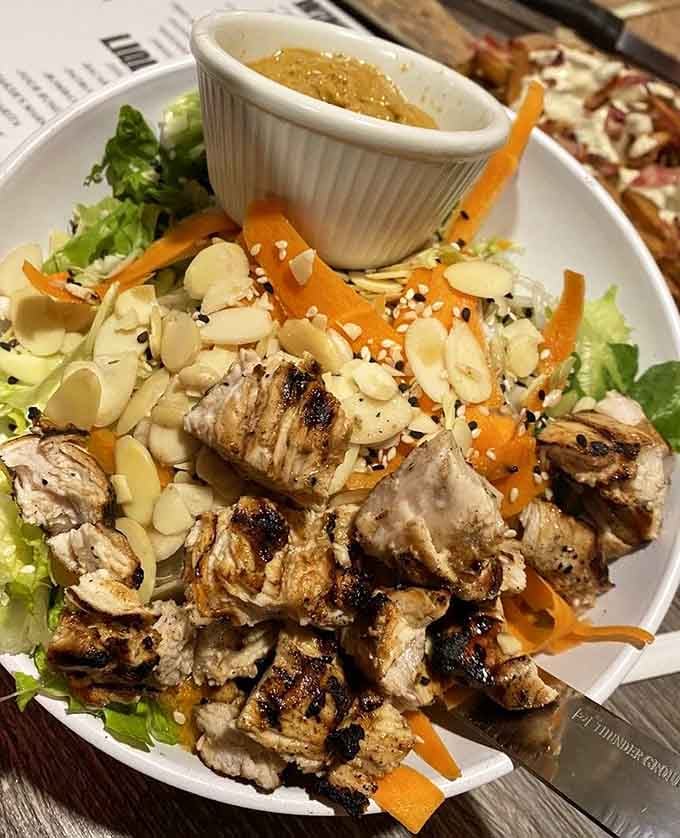Grilled chicken, sliced almonds, shredded carrots, and a ramekin of dipping sauce make this Thai salad look like a genuinely happy surprise.