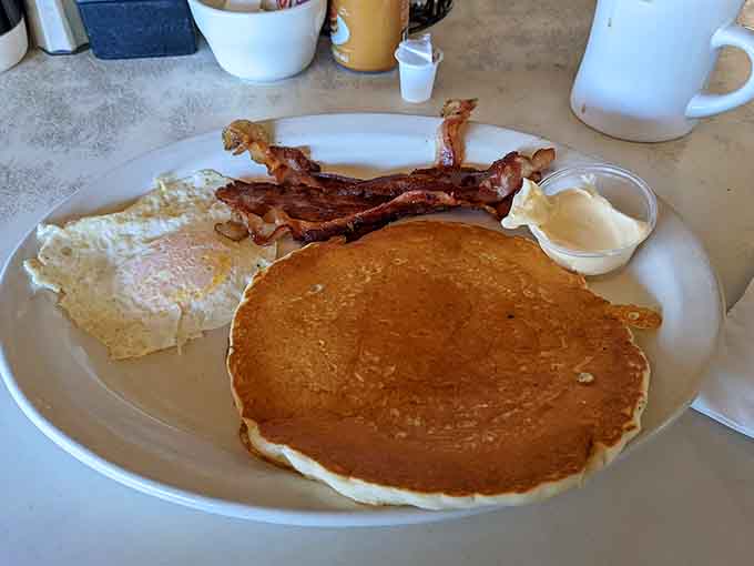 One perfect pancake, two strips of crispy bacon, and two eggs. The holy trinity of breakfast, delivered.