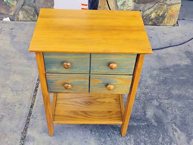 A solid wood side table with painted drawers, the kind of find that makes your living room look intentional.