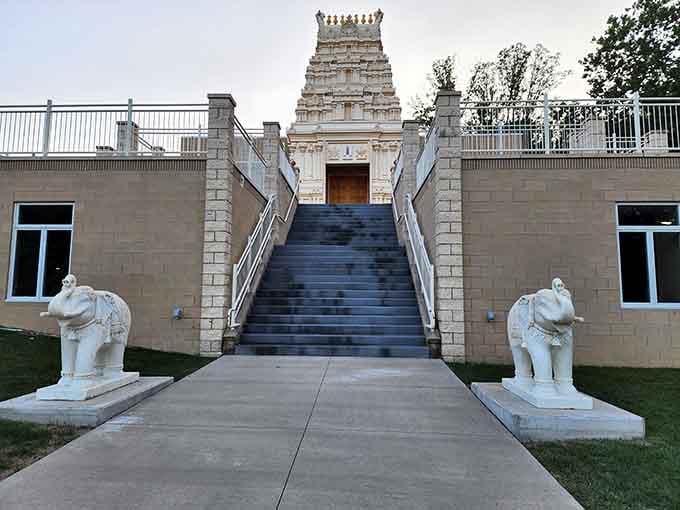 Two white elephant guardians flank the staircase, welcoming you upward toward a gopuram tower that belongs in another century.