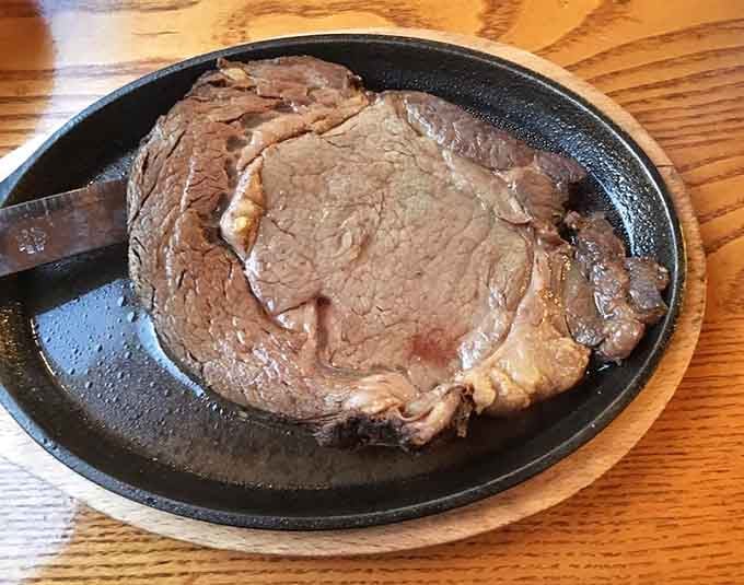 This prime rib arrives on a sizzling skillet, announcing its presence like a delicious drumroll before the main event.