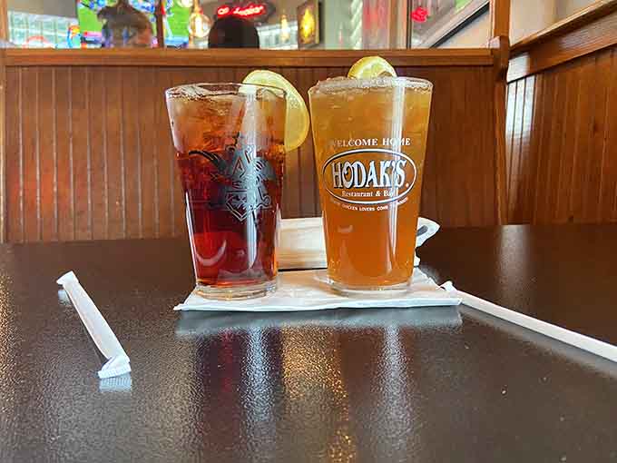 Two tall Hodak's glasses catching the light, one dark cola and one amber tea — the glasses say "Welcome Home," and they mean every word.