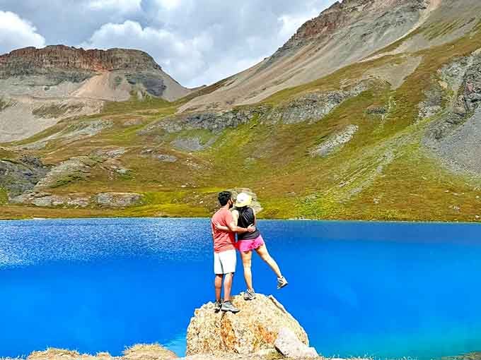 Two people share a kiss on a boulder above that blazing blue water, and honestly, the lake almost steals the moment.