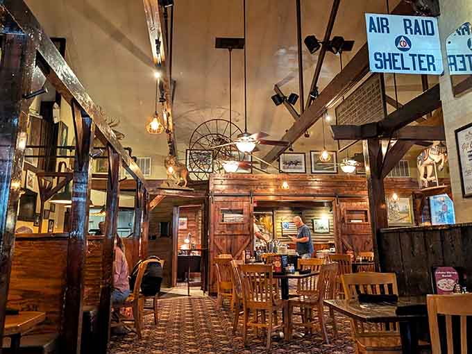 An "Air Raid Shelter" sign hanging above warm wooden beams. History and hospitality sharing the same beautifully cluttered ceiling.