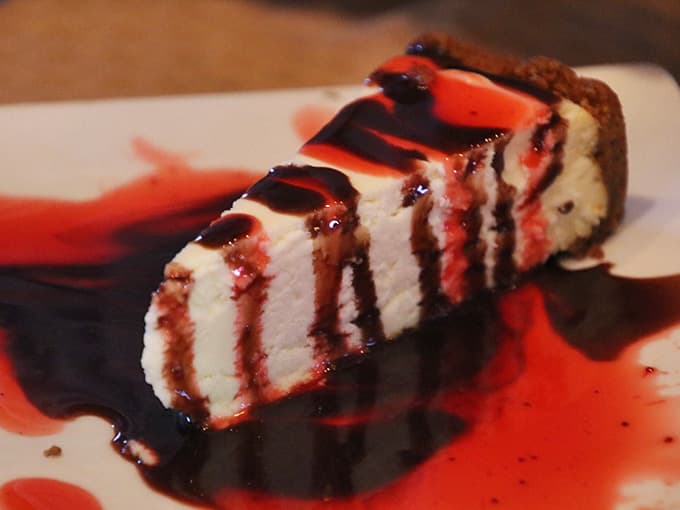 Cheesecake drizzled with berry and chocolate sauce. This dessert isn't asking for attention, it's demanding it.