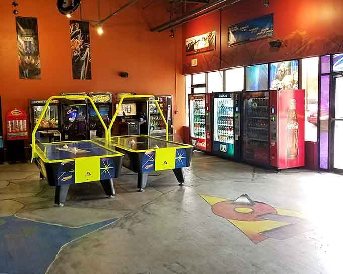 Two neon-trimmed air hockey tables gleaming near the entrance, with cold drinks stocked and ready for the rematch you definitely need.
