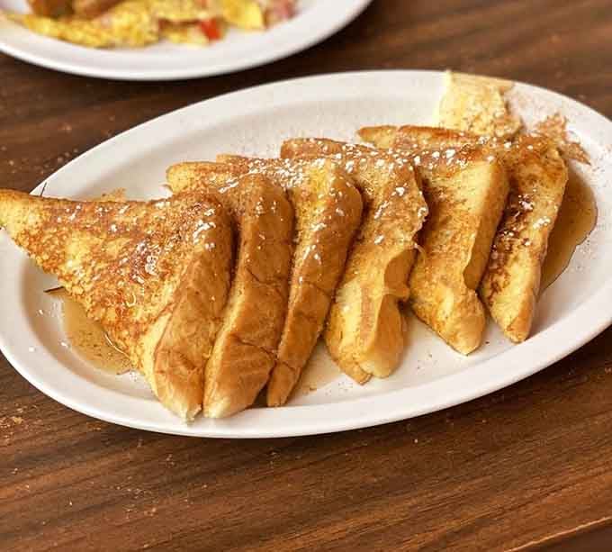 French toast fanned out like a golden sunrise, lightly dusted and ready to make your morning considerably better.