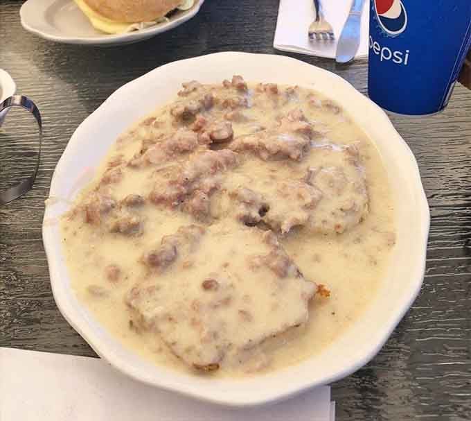Sausage gravy cascading over biscuits like a delicious avalanche of pure breakfast joy and satisfaction.