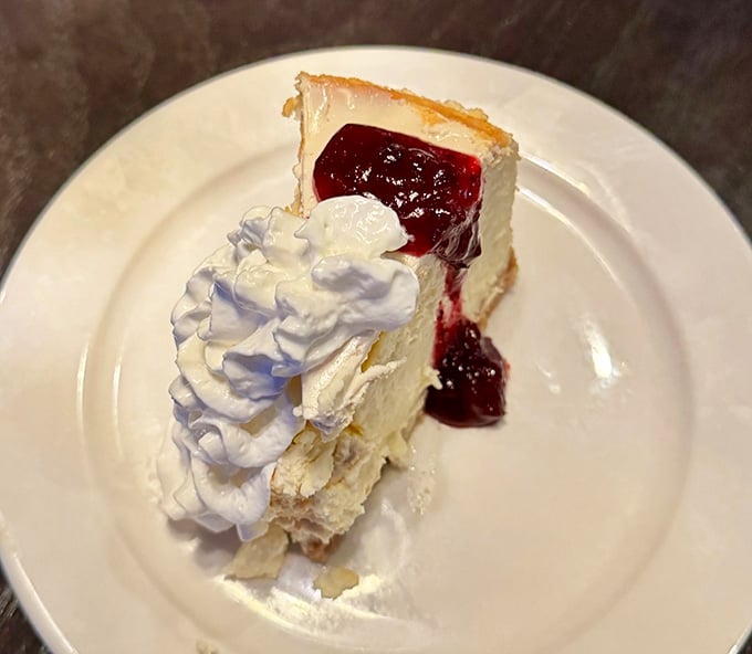 Creamy cheesecake topped with ruby berry sauce and a cloud of whipped cream, dessert that makes skipping it unthinkable.