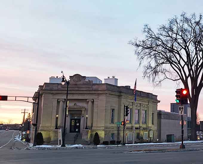 The Stephenson Public Library glows warmly at dusk, its neoclassical stone facade looking like the kind of place where very important decisions get made quietly.