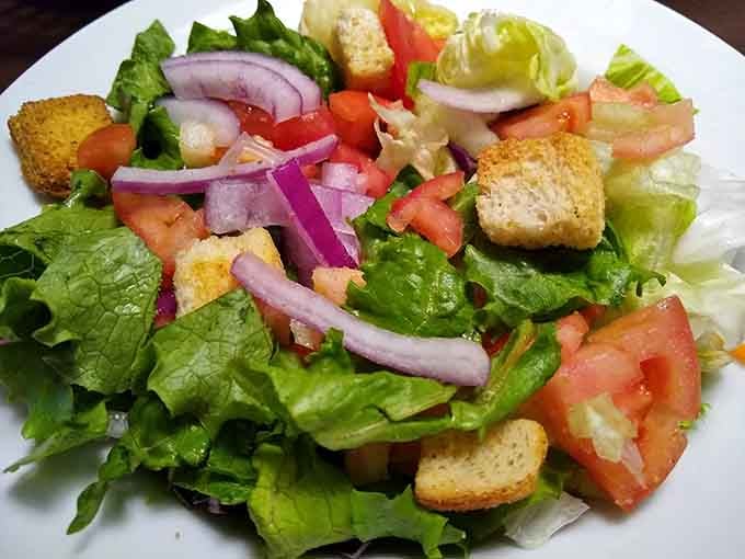 Crisp lettuce, red onion, tomato, and croutons. Even the salad here looks like it's trying to impress somebody.