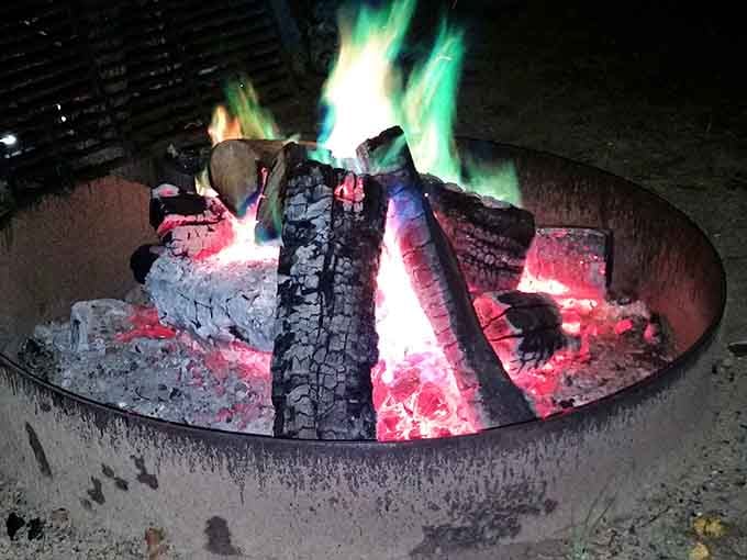 Green and pink flames dancing in a campfire ring at night, proof that nature has always had a flair for drama.
