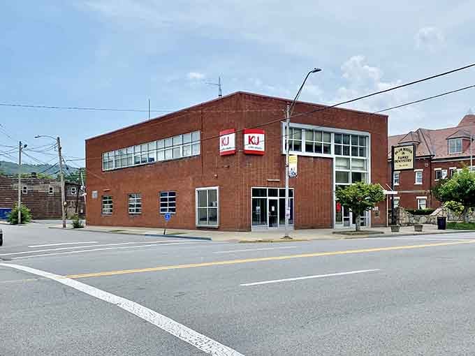 The KJ building anchors this corner with solid red brick confidence, mountains peeking over the roofline behind it.