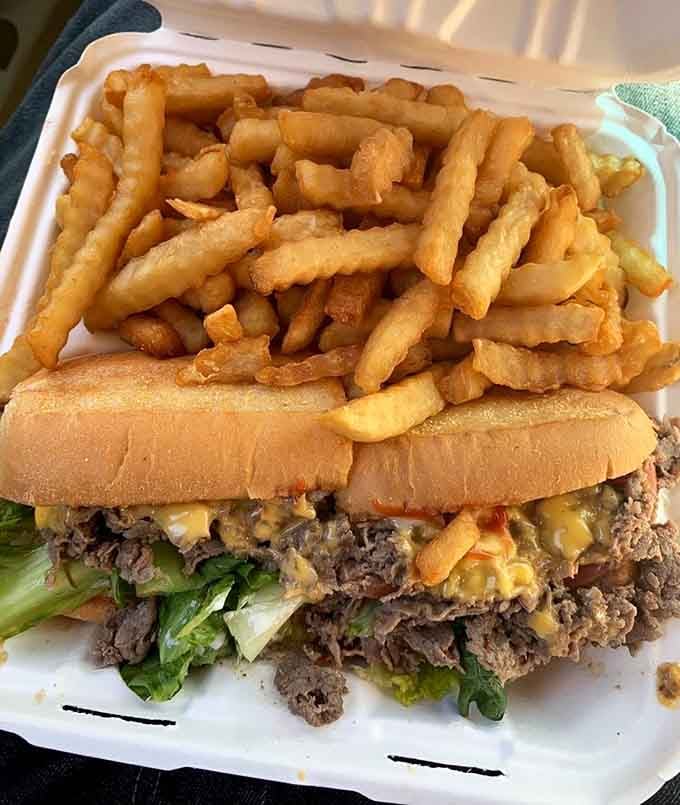 A Philly cheesesteak deluxe buried under crinkle fries. Somewhere, a napkin is already nervous about this situation.
