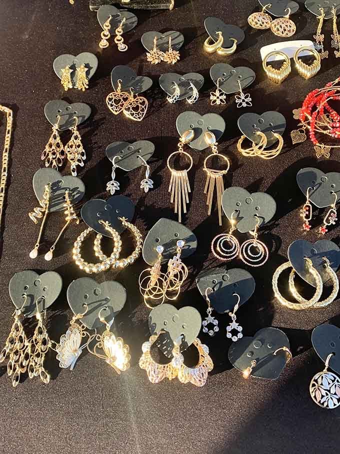 Gold-toned earrings fanned across dark velvet, each pair catching the light like it's already dressed up for Saturday night.