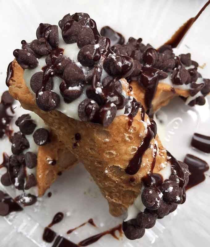Cannoli stuffed generously and drizzled with chocolate sauce, Italy called and it approves of this ending to your meal.