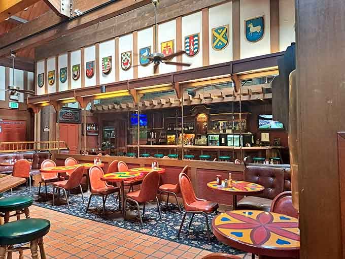 Colorful heraldic shields line the walls above the bar area, giving this corner a distinctly old-world European tavern personality.
