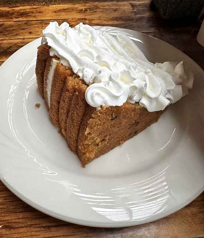 A generous slice of cake topped with clouds of whipped cream. Dessert here is not an afterthought.