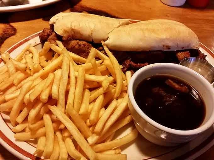 A French dip sandwich with a generous side of fries and a dark, rich dipping sauce ready for action.