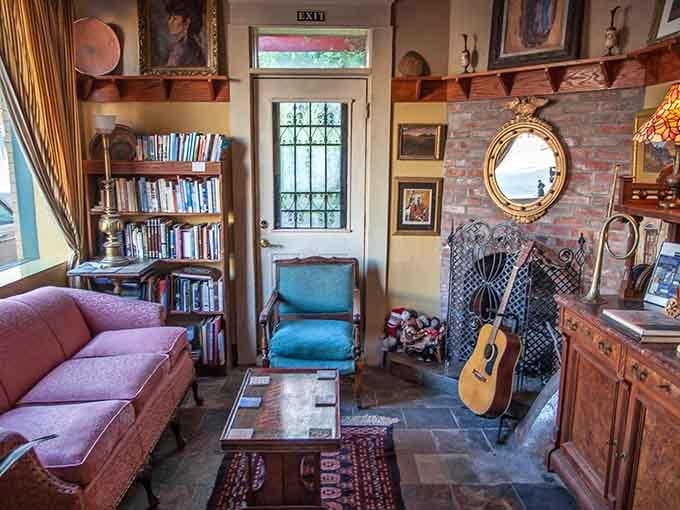 Bookshelves, a guitar by the fireplace, a pink sofa, and a round mirror. This parlor is basically a personality test you pass automatically.