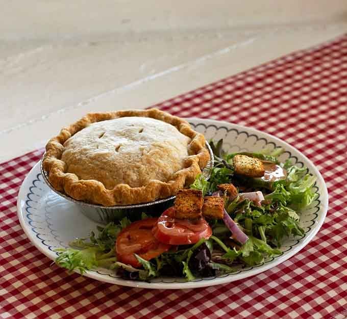 A golden-crusted chicken pot pie arrives with a side salad, proving comfort food can look this good.