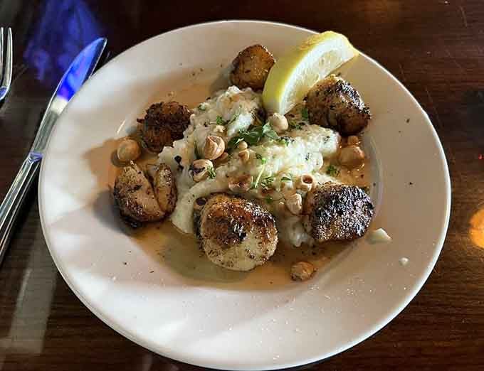 Beautifully seared scallops resting on creamy mash, scattered with hazelnuts and finished with lemon, elegant without trying too hard.