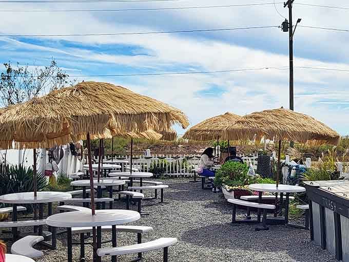 Thatched umbrellas, open sky, and a cool coastal breeze make this outdoor patio feel like a mini vacation from everything.