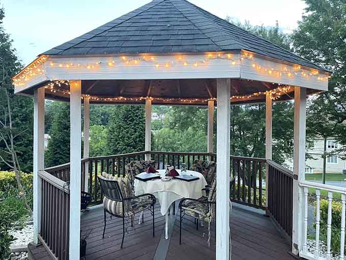 A gazebo wrapped in string lights, set with white linens, because dinner outside should always feel this good.