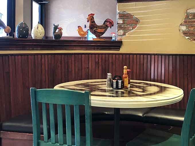 Ceramic roosters keeping watch over a teal chair and a round table. The breakfast theme runs deep here.