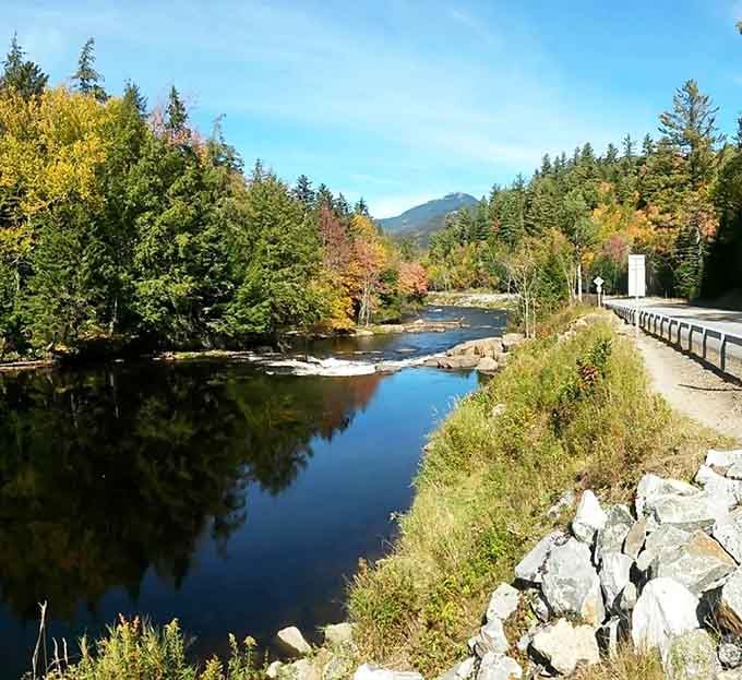 The East Branch Ausable River runs alongside the road like it's quietly showing off its best autumn outfit.
