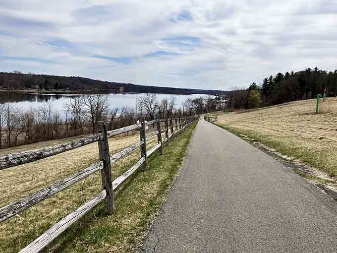 A weathered split-rail fence guiding your eye toward the wide, still water beyond is early spring storytelling at its most understated and beautiful.