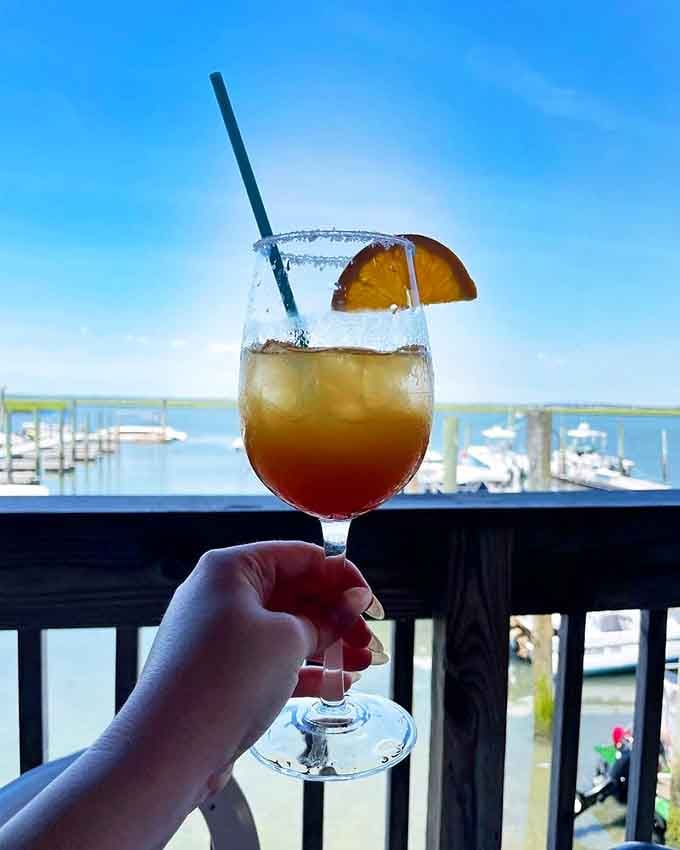A tequila sunrise cocktail held up against a marina backdrop. Honestly, the view is almost as good as the drink.