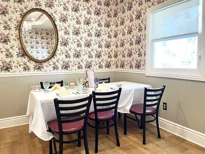 Floral wallpaper and an oval mirror create an intimate dining nook that feels wonderfully old-fashioned.