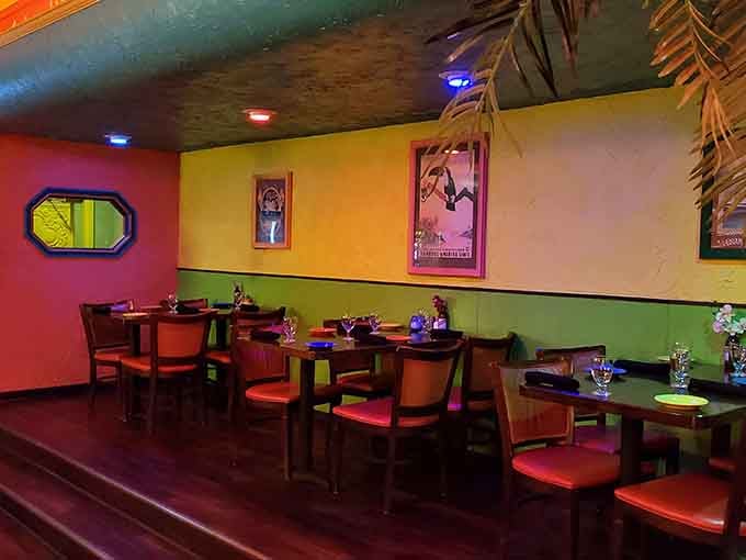 Moody lighting, red cushioned chairs, and tropical artwork on green and yellow walls, this corner means serious business.