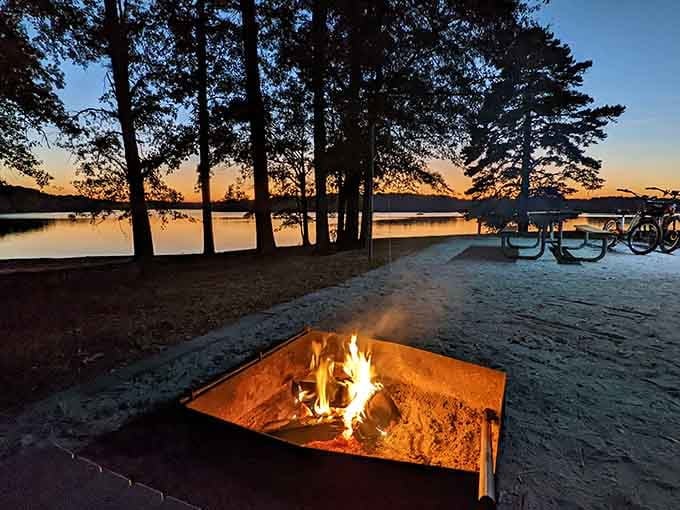 A campfire crackling at dusk with the lake glowing behind it. This is the screensaver you actually want to live inside.