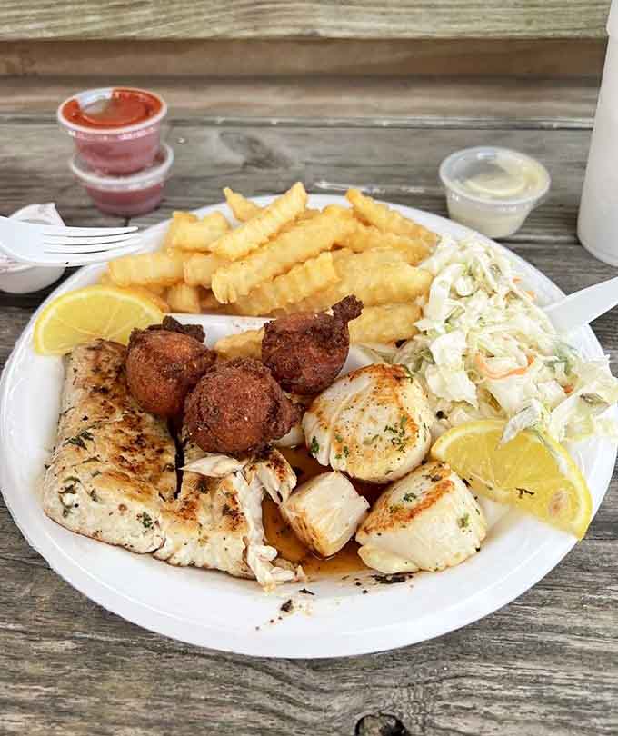 Grilled scallops and fish with golden hushpuppies front and center. Every element on this plate earns its spot.