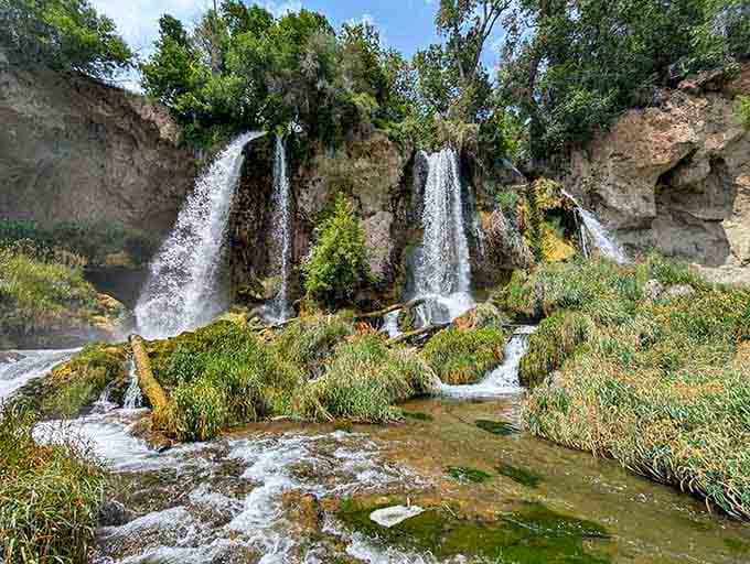 Three waterfalls cascade side by side over moss-covered limestone, creating a symphony of rushing water and natural beauty.