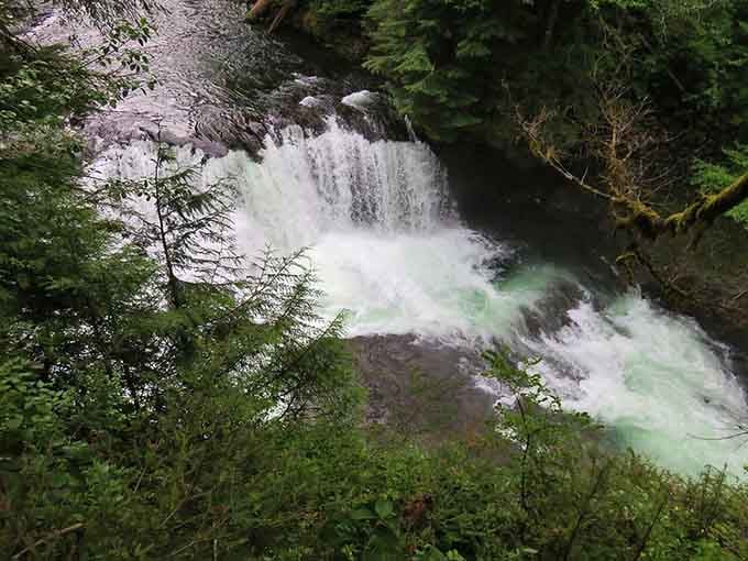 Emerald water swirls at the base where the falls create a churning pool of glacial-fed mountain freshness.