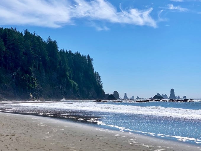 Sunlight dances across the wet sand as waves roll in, framing those iconic sea stacks in pure Pacific glory.