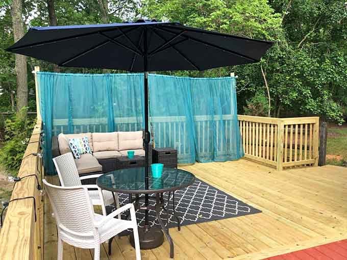 A deck with teal curtains and patio furniture, your own private outdoor living room, minus the HOA rules.