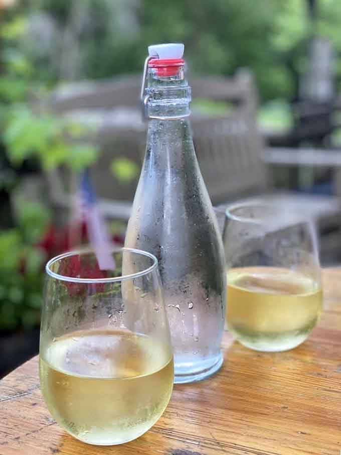 A chilled bottle of white wine on the outdoor patio, with Cedar Creek greenery in the background &mdash; this is the definition of a good afternoon.