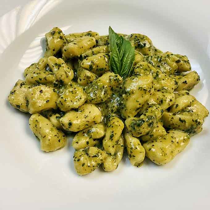 Soft gnocchi blanketed in vibrant pesto and crowned with fresh basil, this plate smells like a Ligurian daydream.