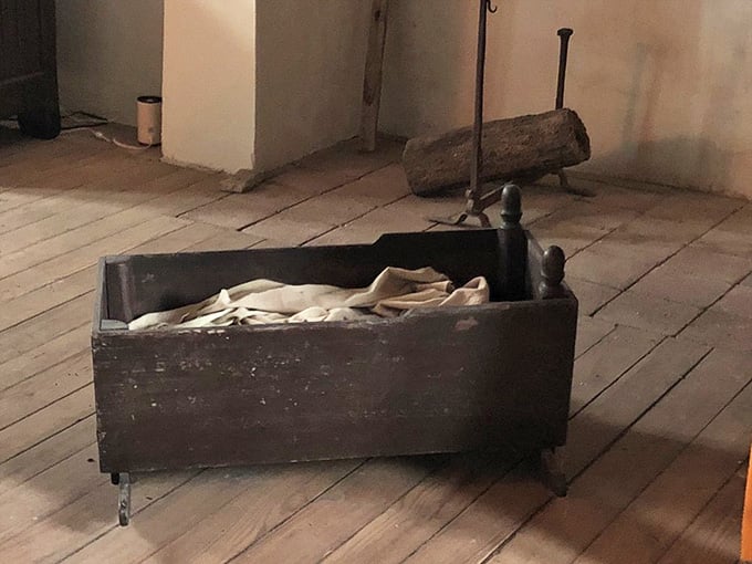 A wooden cradle on ancient floorboards, quietly reminding you that real lives unfolded in every corner of this house.