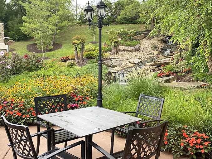 A garden table with a front-row view of a cascading waterfall and blooming flowers. Nature put in the work here.
