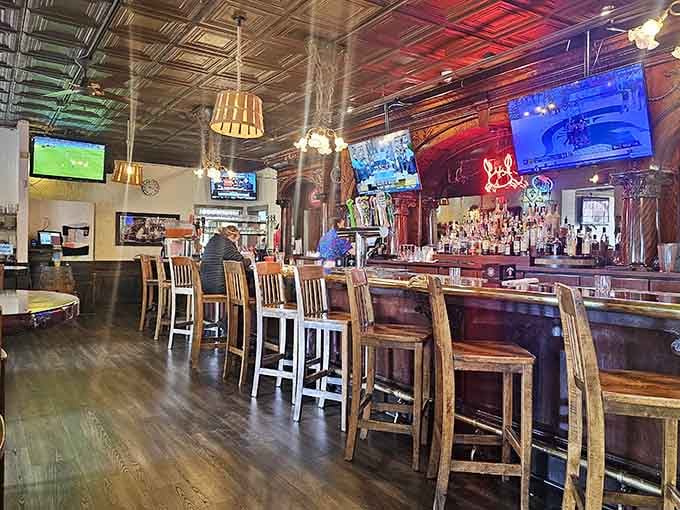 A full bar with a tin ceiling overhead and multiple TVs glowing. This is where great meals begin and great stories end.