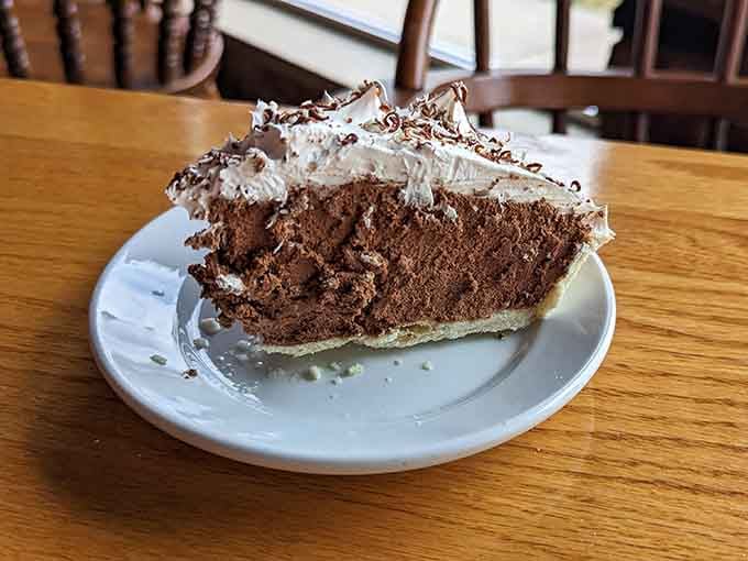 A slice of chocolate cream pie topped with whipped cream and chocolate shavings. Dessert doesn't negotiate, it just wins.