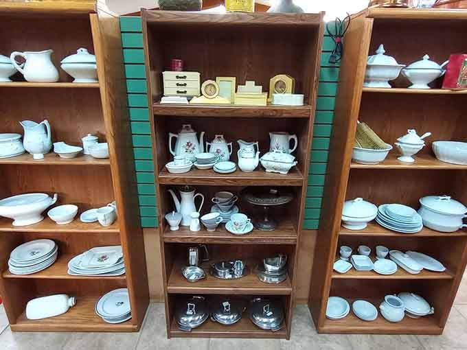 Shelves of white ironstone pitchers, tureens, and tea sets, the kind of dinnerware that makes Sunday dinner feel like an occasion.