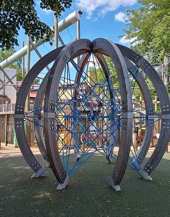 This striking geometric climbing sphere, framed by blue sky and trees, looks like modern art that somehow dares you to climb inside it.