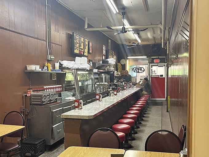 The long counter stretches toward the kitchen like a runway, and every seat on it leads somewhere delicious.