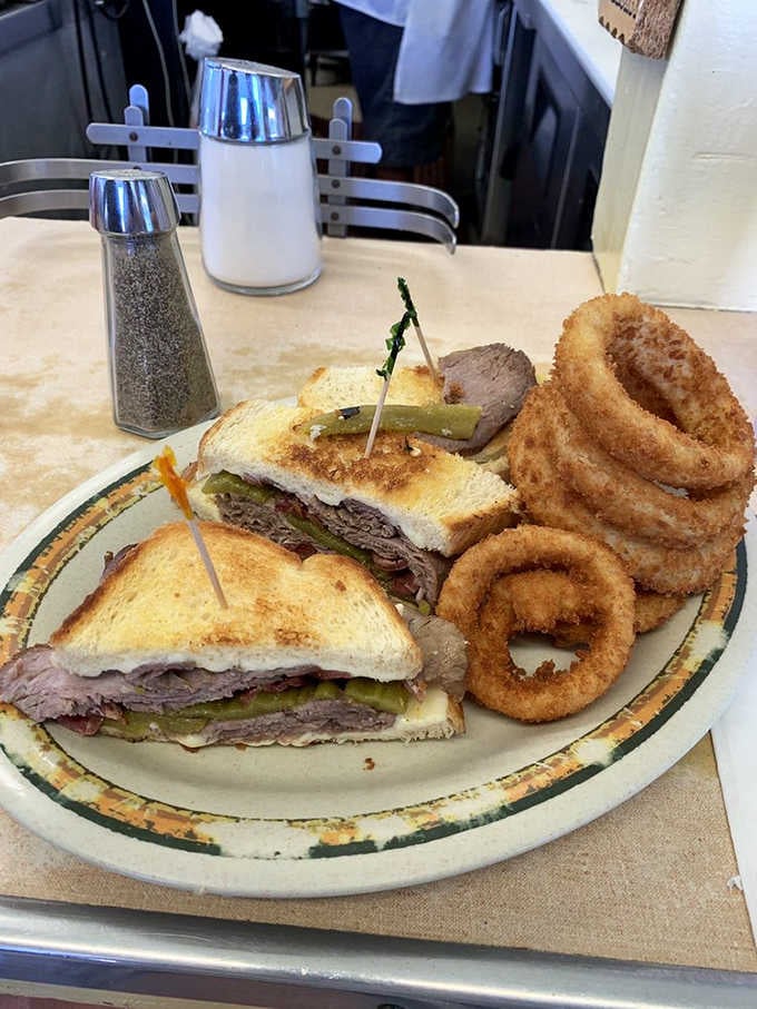 A roast beef sandwich with pickles and onion rings on the side. Lunch doesn't get more classic.